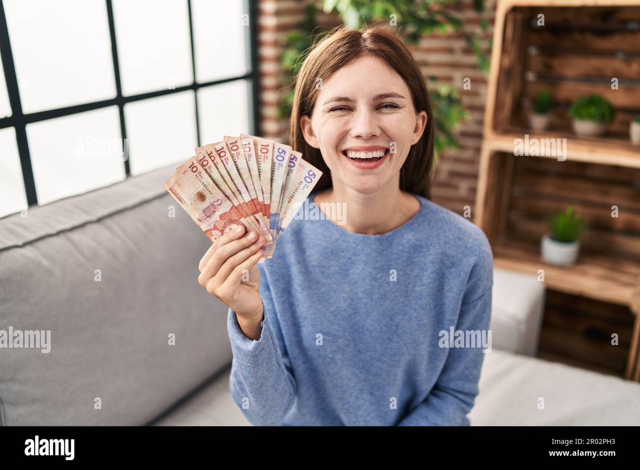Young brunette woman holding colombian pesos looking positive and happy ...