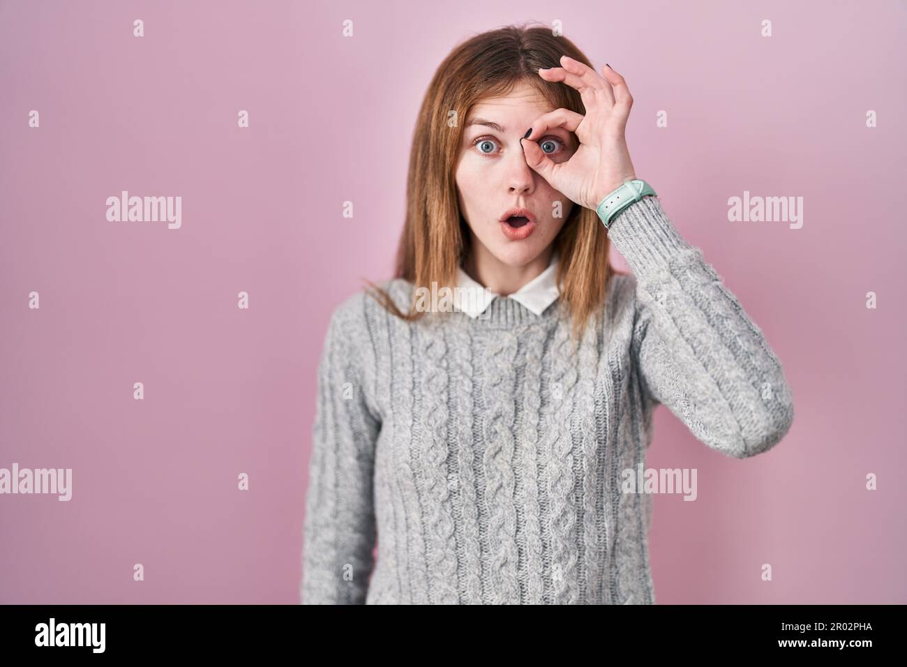 Beautiful woman standing over pink background doing ok gesture shocked ...