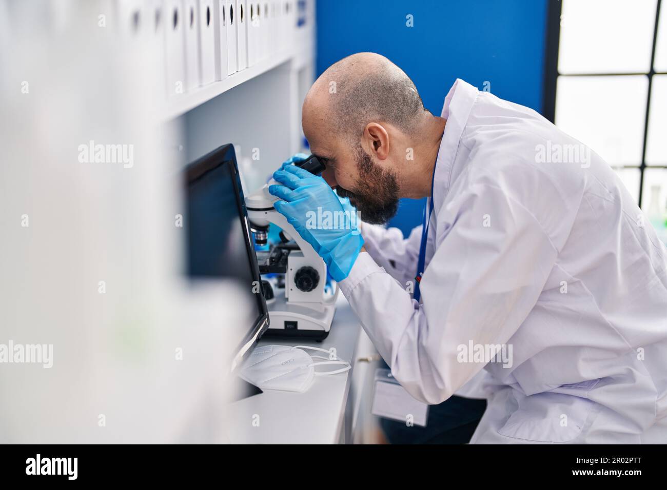 Young bald man scientist using microscope at laboratory Stock Photo - Alamy
