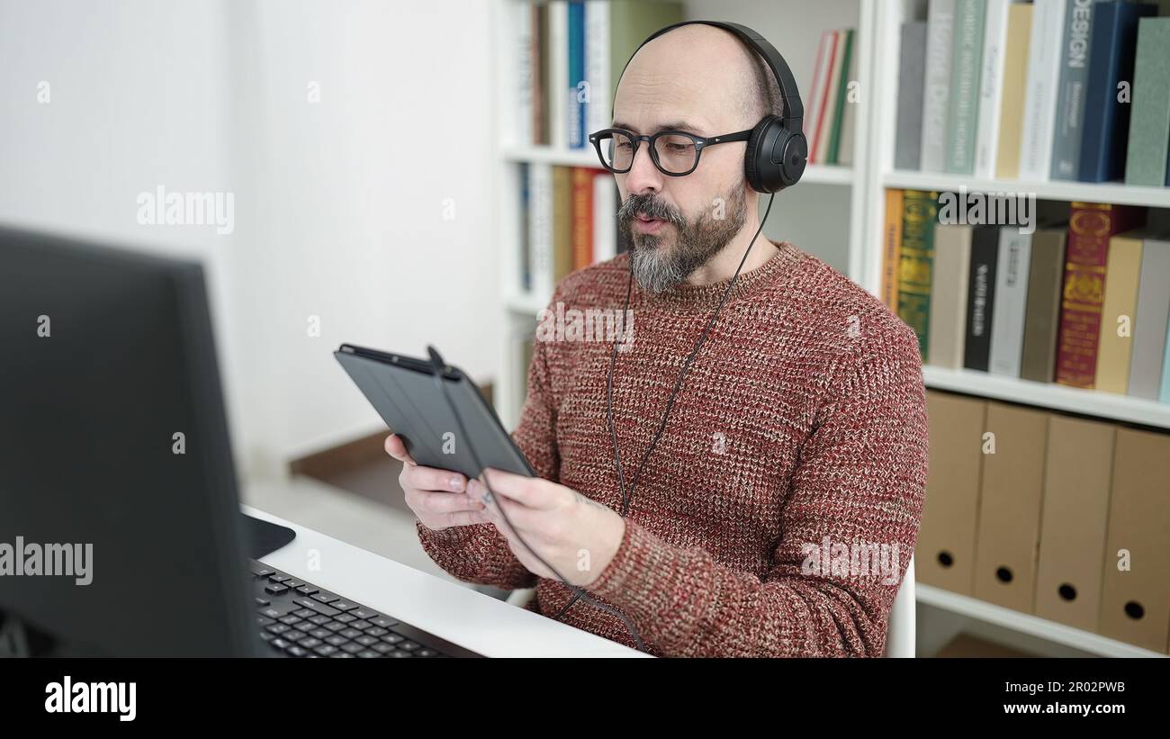 Young bald man student using touchpad studying at university classroom ...
