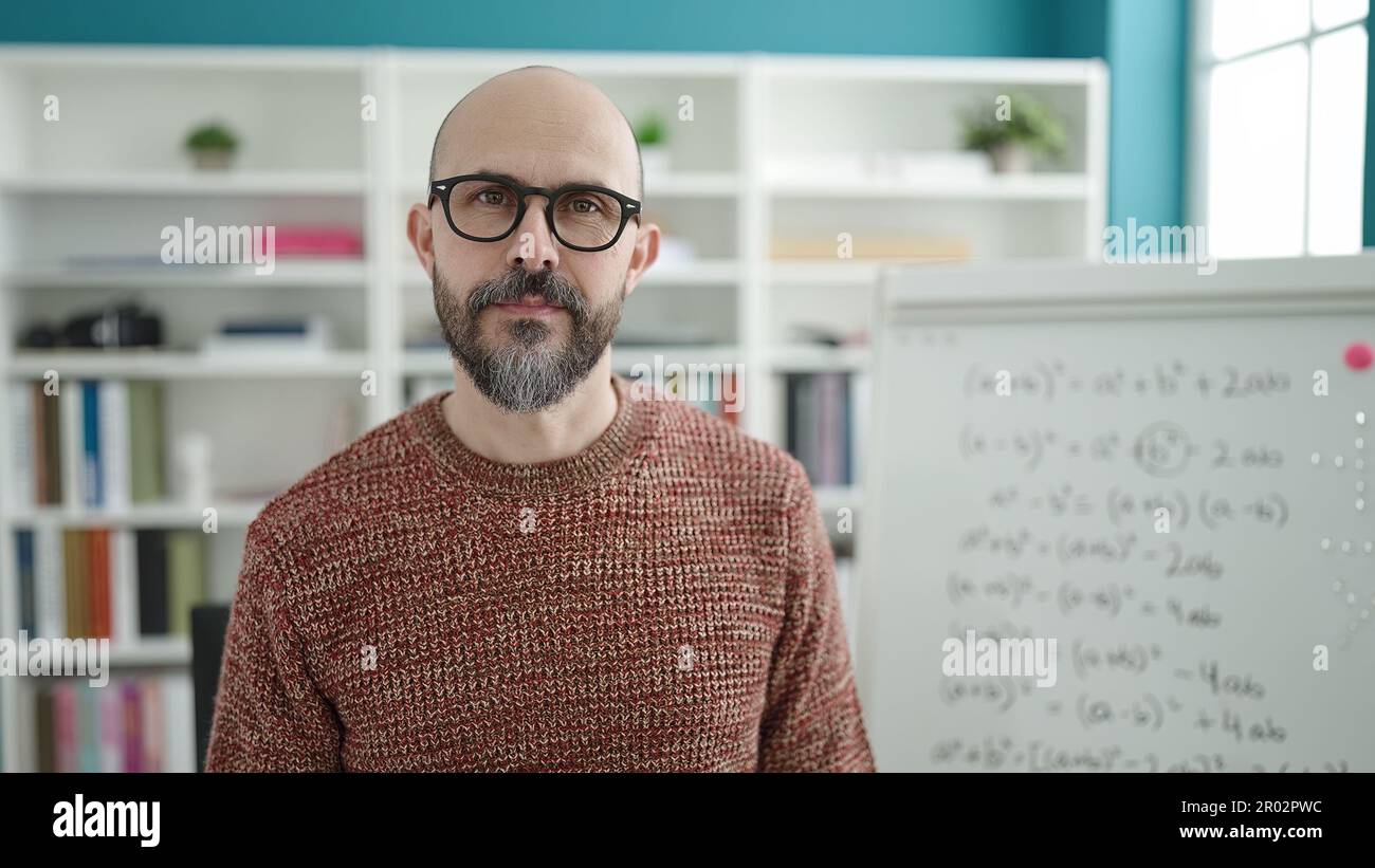 Young bald man teacher standing with relaxed expression at university ...