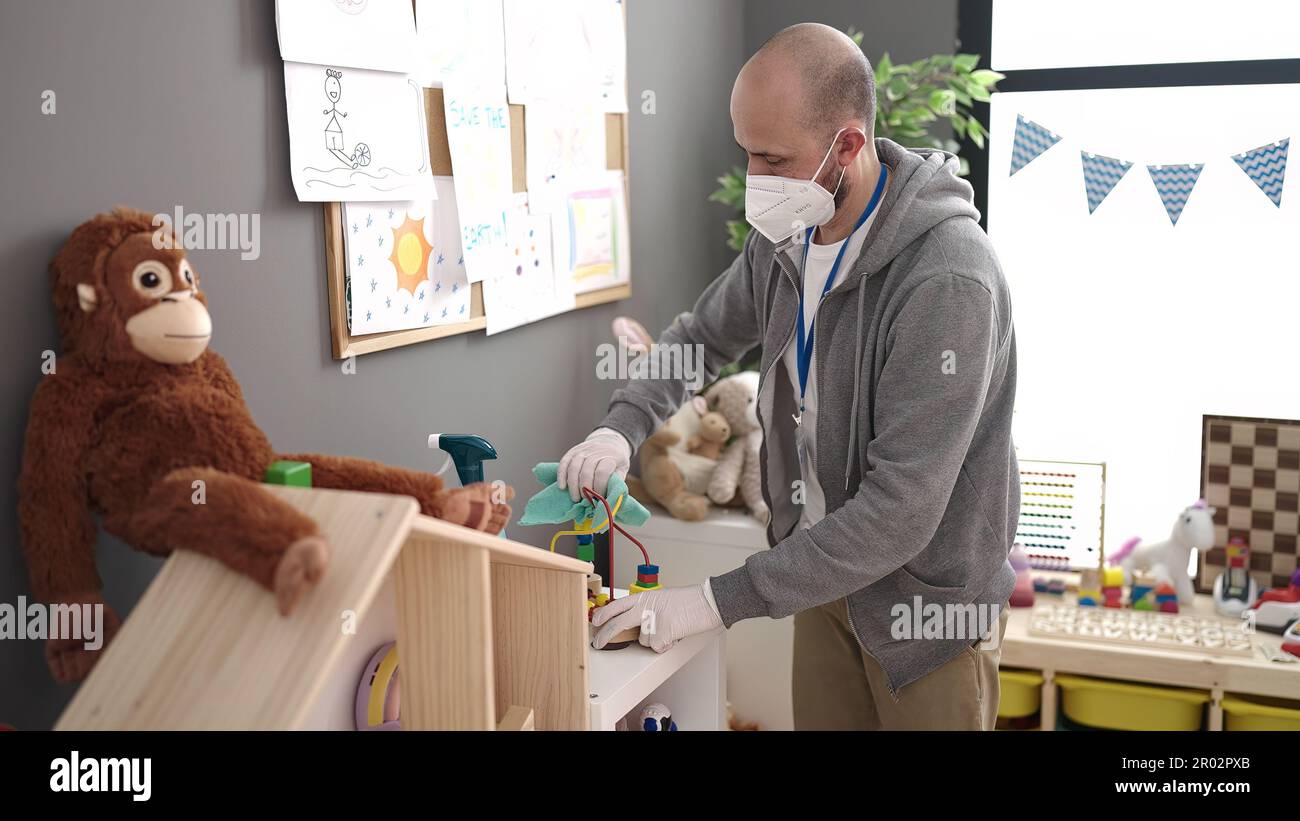 Young bald man preschool teacher wearing medical mask cleaning at ...