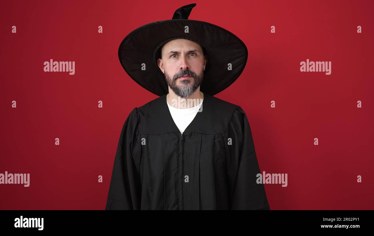 Young bald man wearing wizard costume standing over isolated red ...