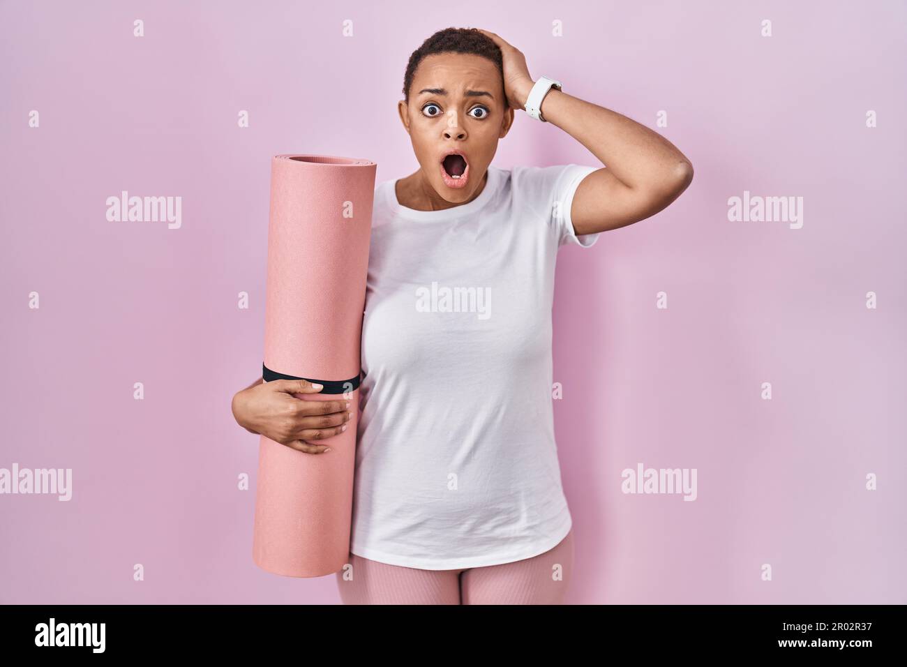 Beautiful african american woman holding yoga mat crazy and scared with ...