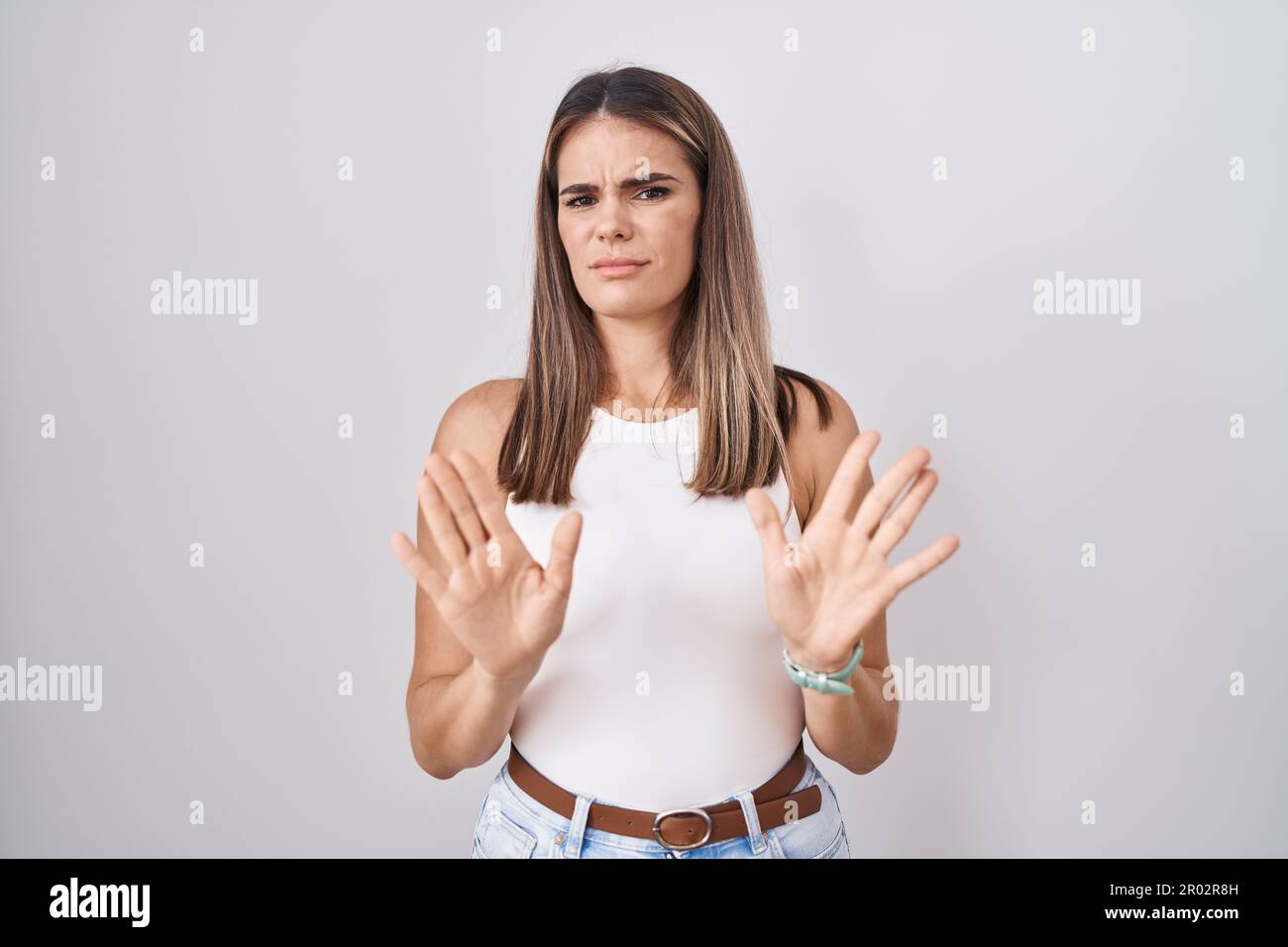 Hispanic young woman standing over white background moving away hands ...