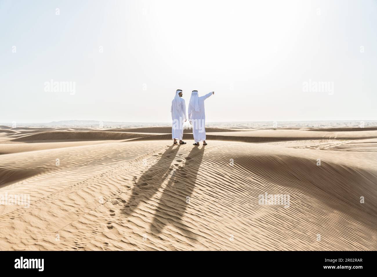 Two middle-eastern men wearing traditional emirati arab kandura bonding ...