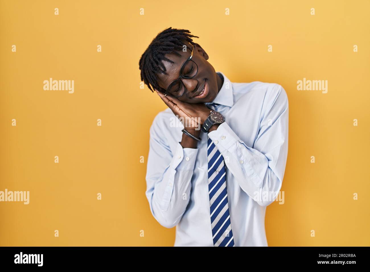 African man with dreadlocks standing over yellow background sleeping ...