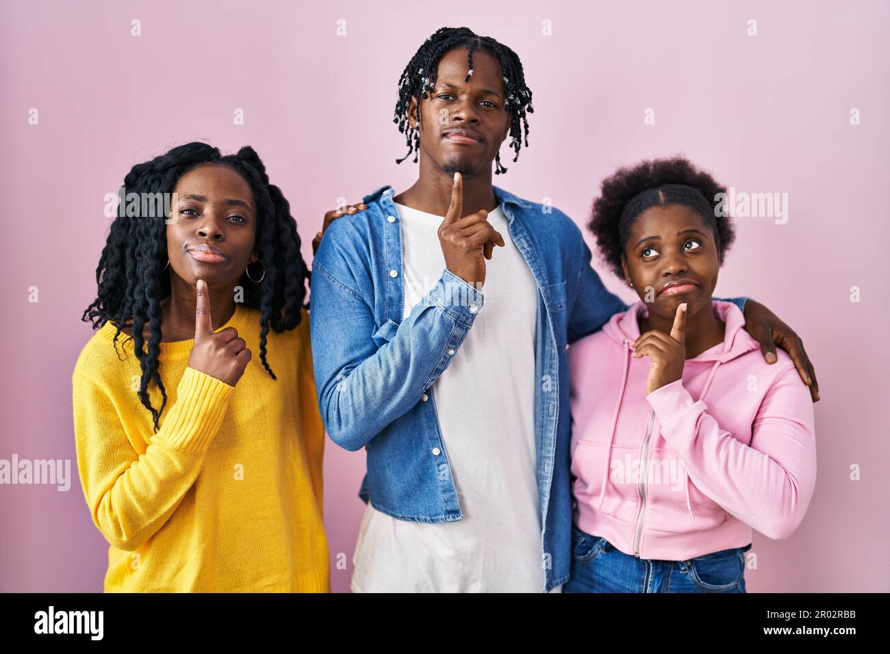 Group of three young black people standing together over pink ...