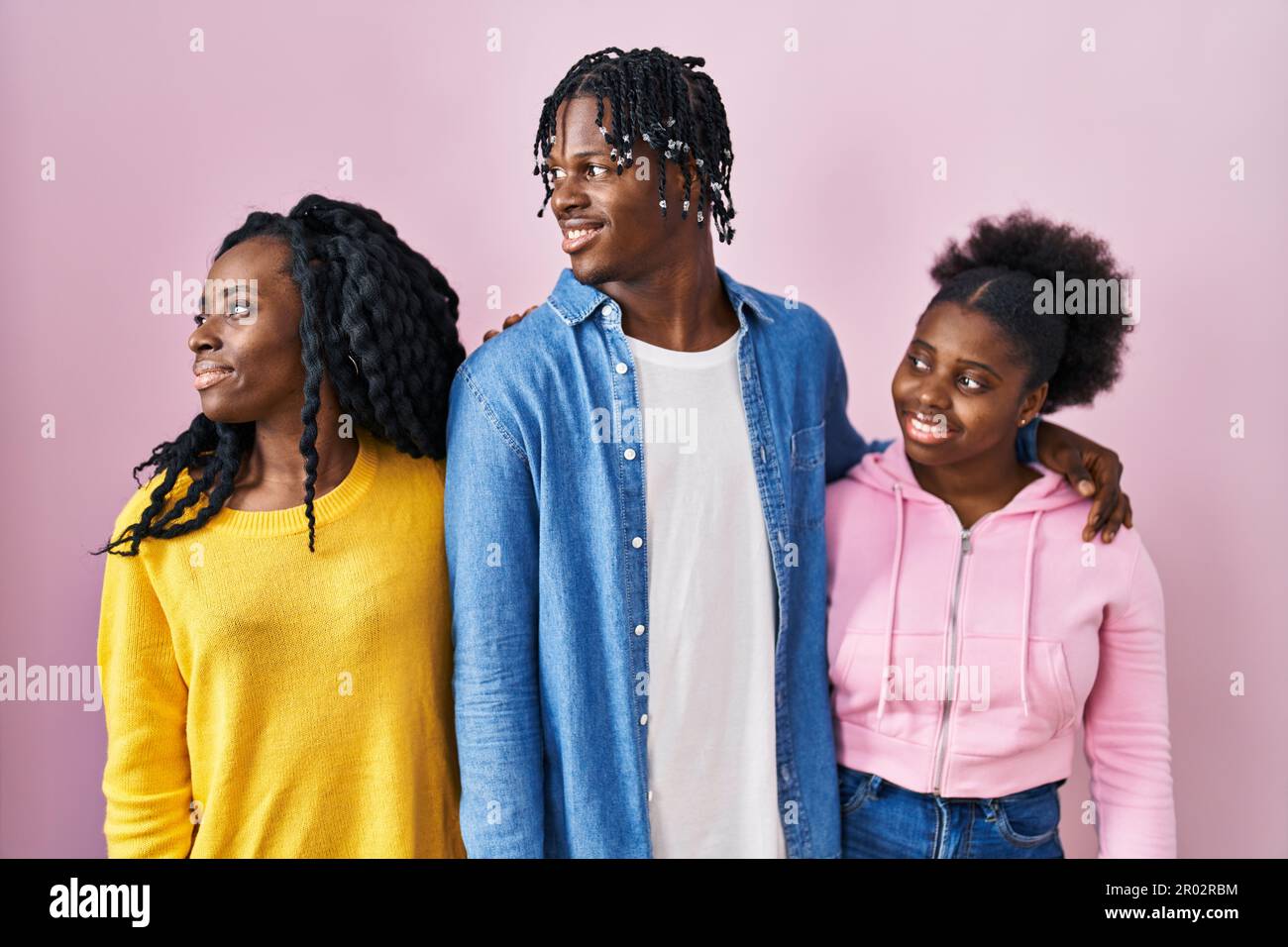 Group of three young black people standing together over pink ...