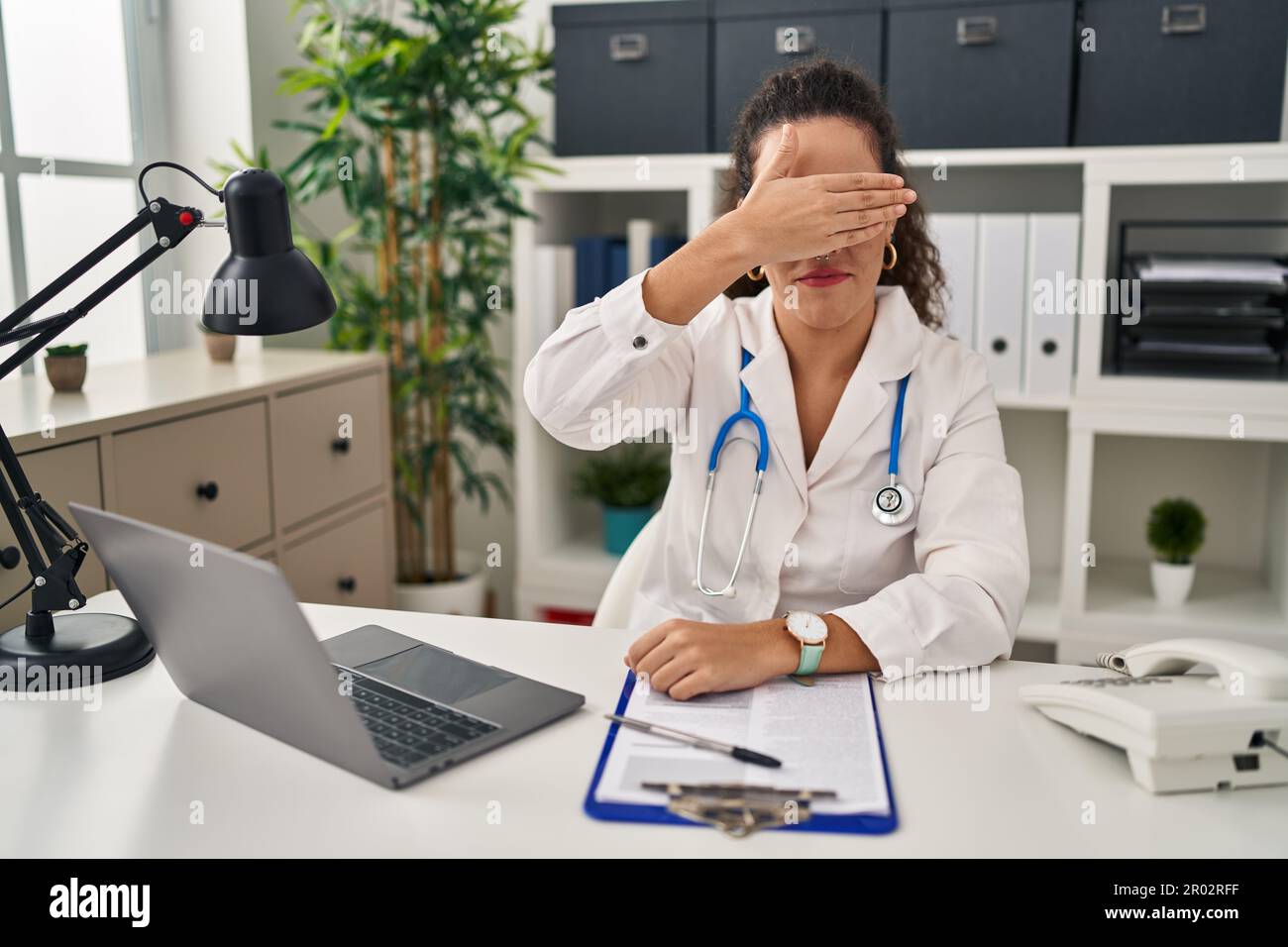 Young hispanic woman wearing doctor uniform and stethoscope covering ...