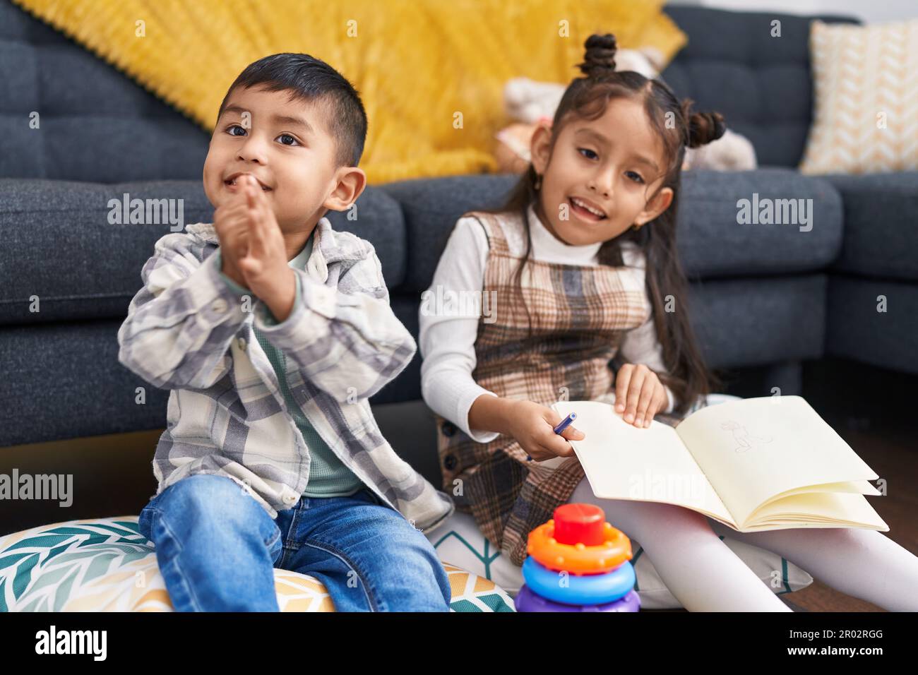 Adorable boy and girl reading book clapping hands at home Stock Photo ...