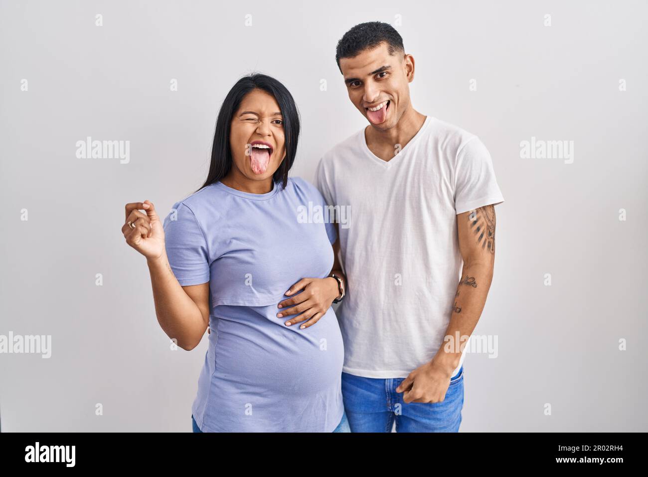 Young hispanic couple expecting a baby standing over background ...