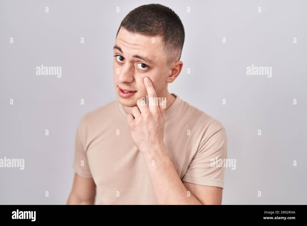 Young man standing over isolated background pointing to the eye ...