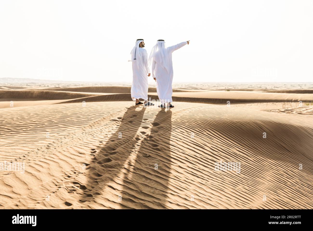 Two middle-eastern men wearing traditional emirati arab kandura bonding ...