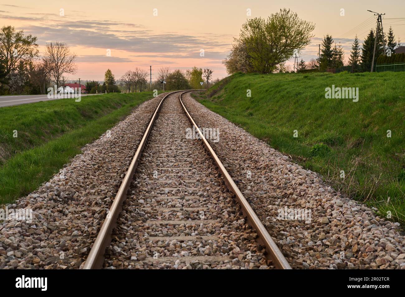 A single railway line on the embankment along the road bending over the ...