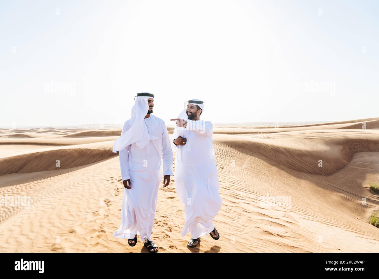 Two middle-eastern men wearing traditional emirati arab kandura bonding ...