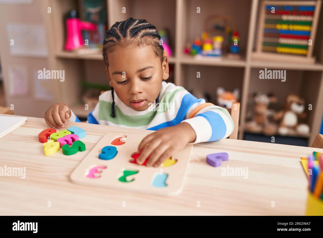 African american boy playing with maths puzzle game sitting on table at ...