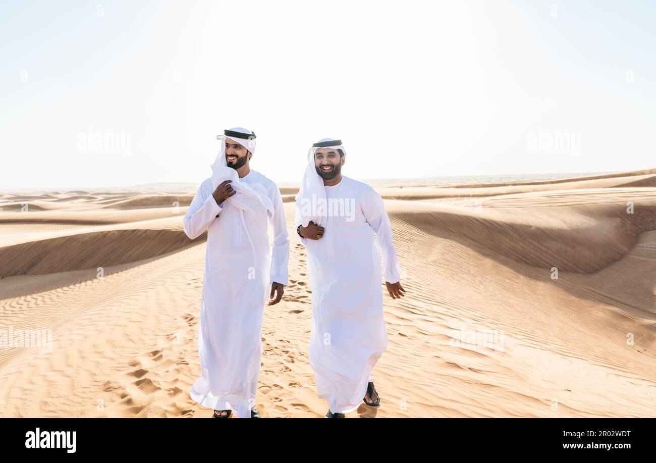 Two middle-eastern men wearing traditional emirati arab kandura bonding ...