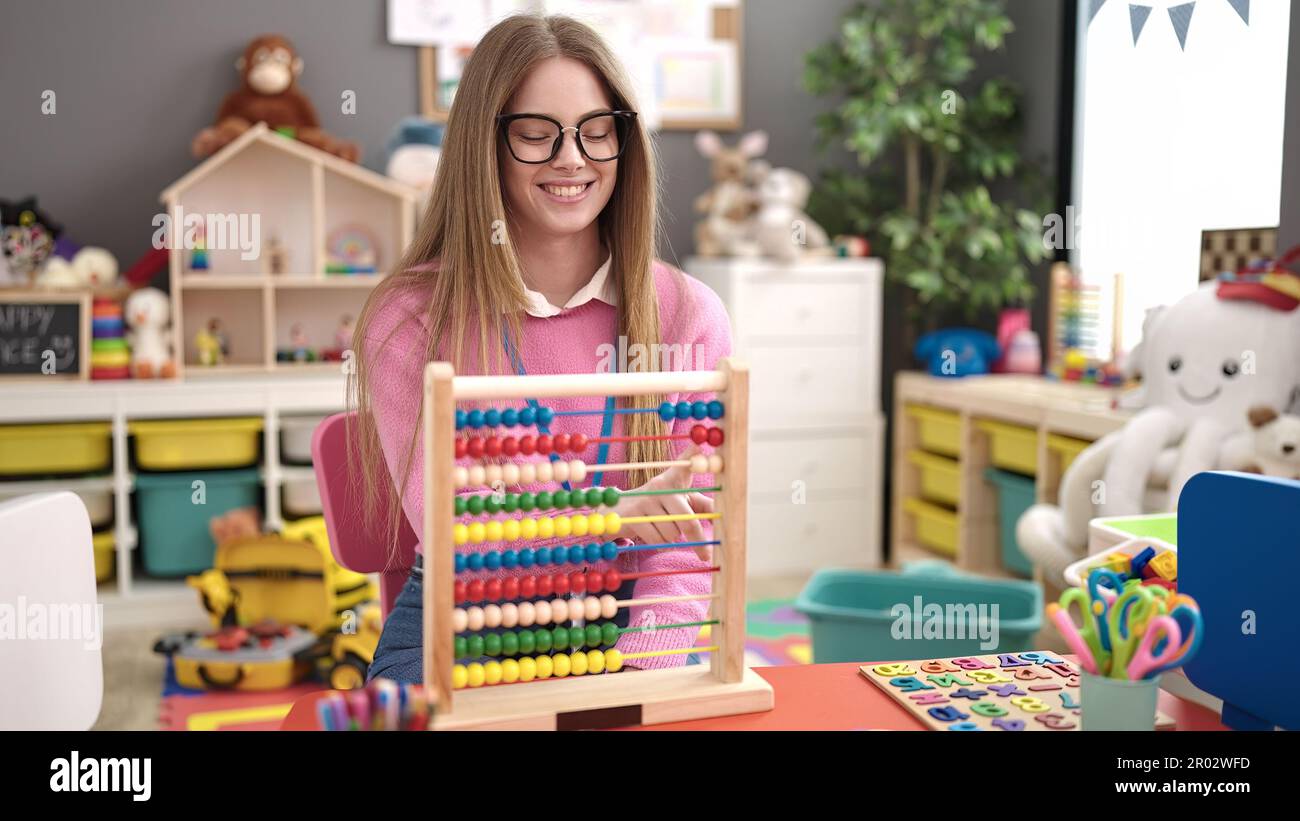 Young blonde woman preschool teacher teaching maths with abacus at ...