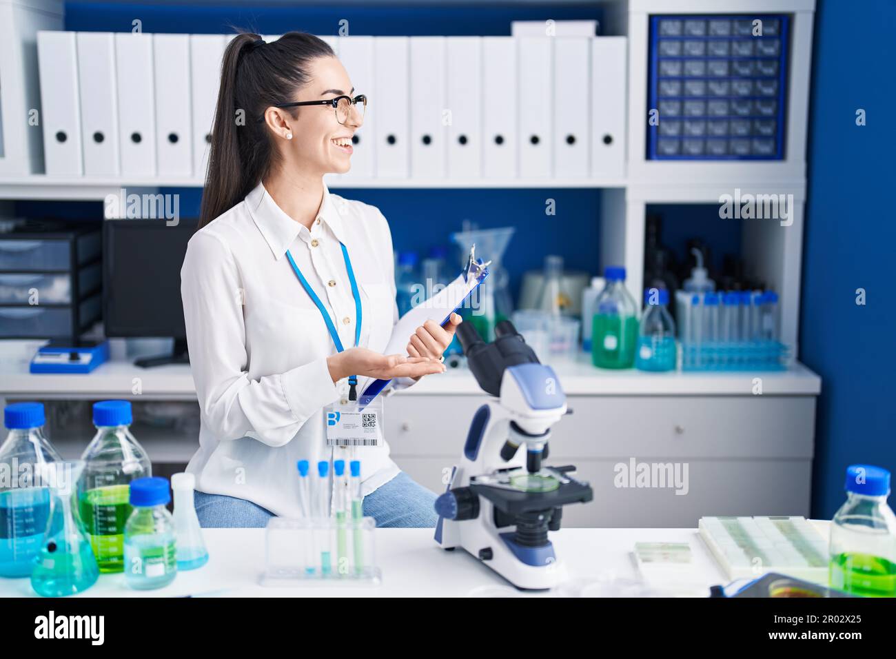 Young brunette woman working at scientist laboratory looking to side, relax profile pose with ...