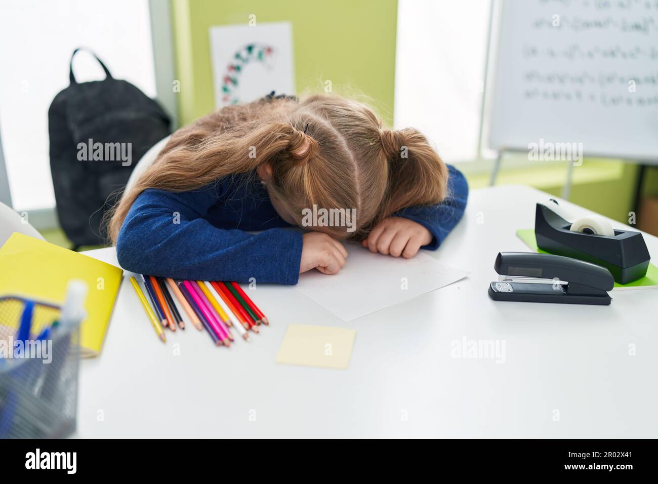 Adorable blonde girl student sleeping with head on table at classroom ...
