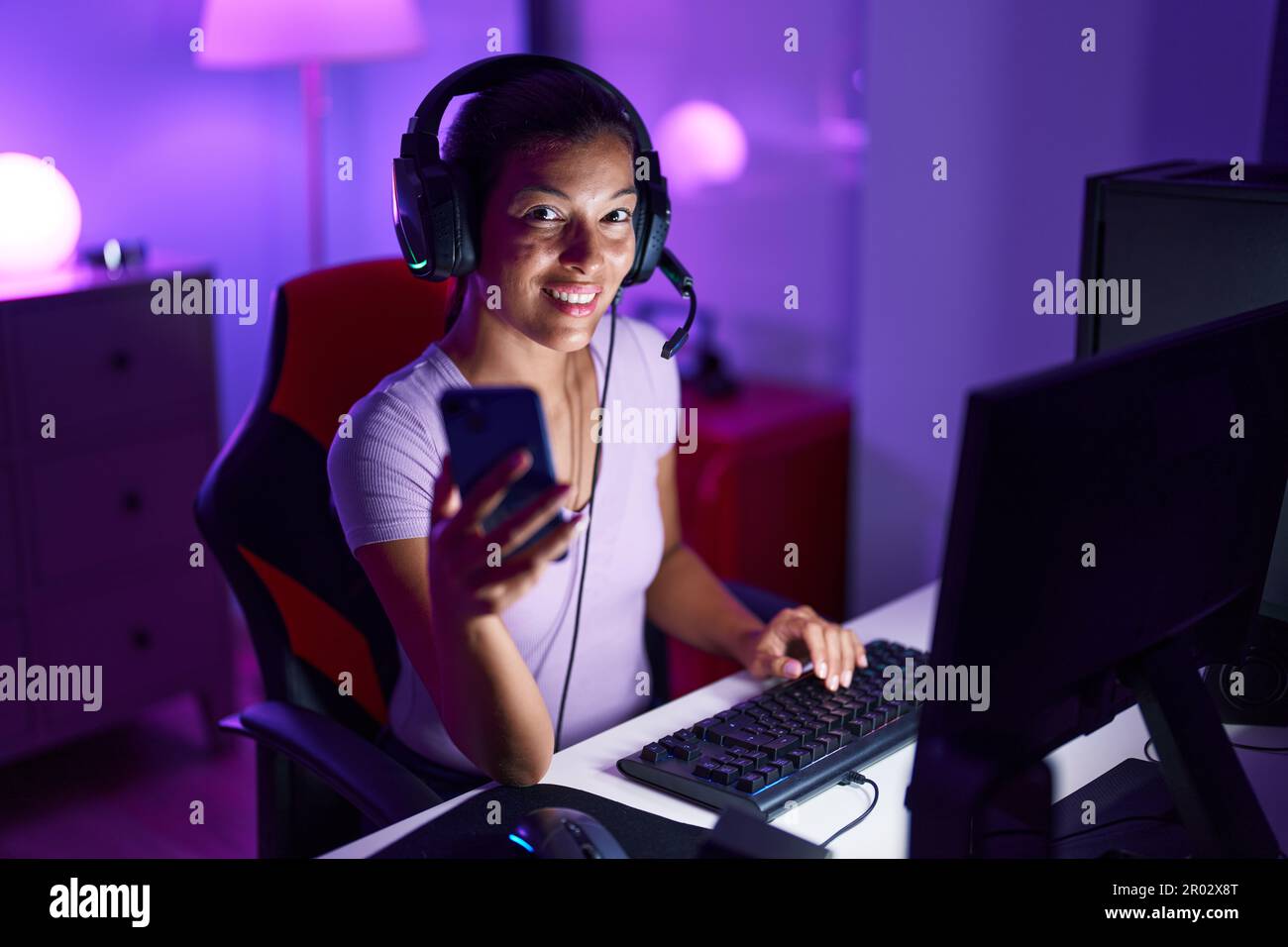 Young beautiful hispanic woman streamer using computer and smartphone ...