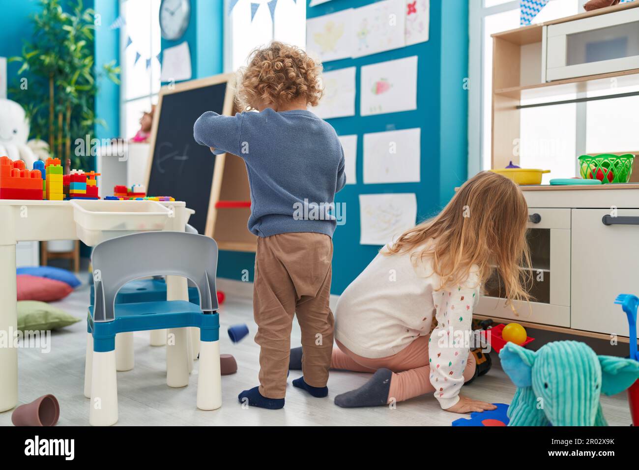 Adorable boy and girl standing with relaxed expression playing at ...