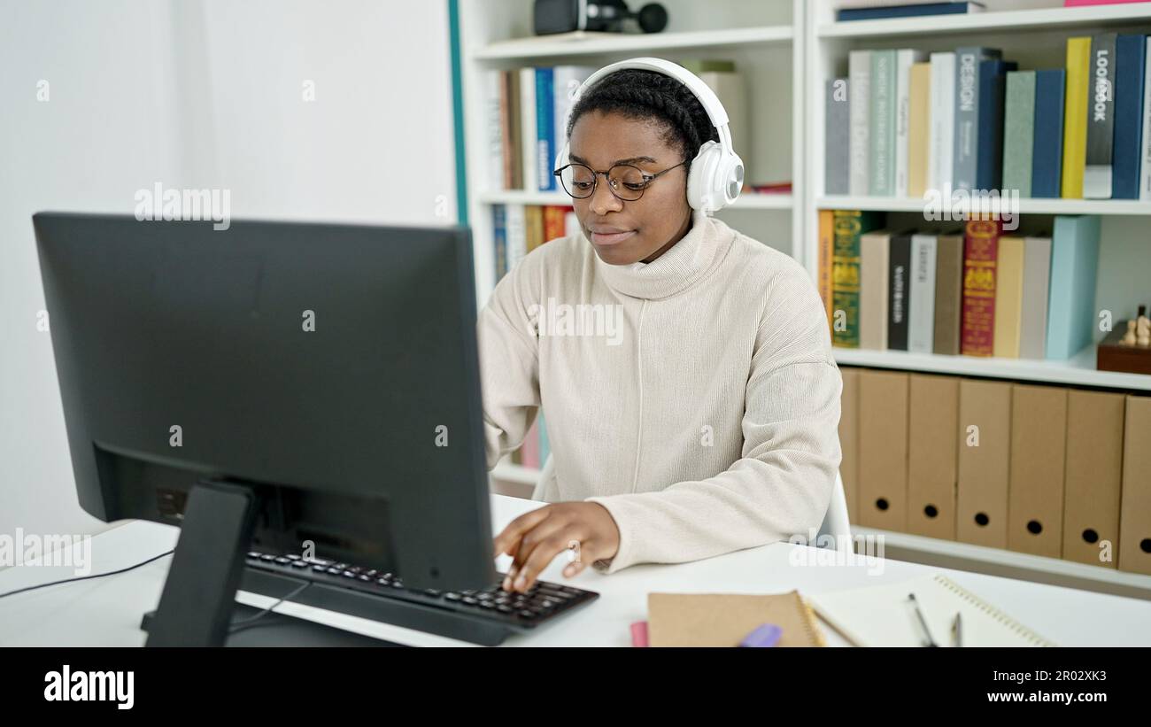 African american woman student using computer and headphones studying ...