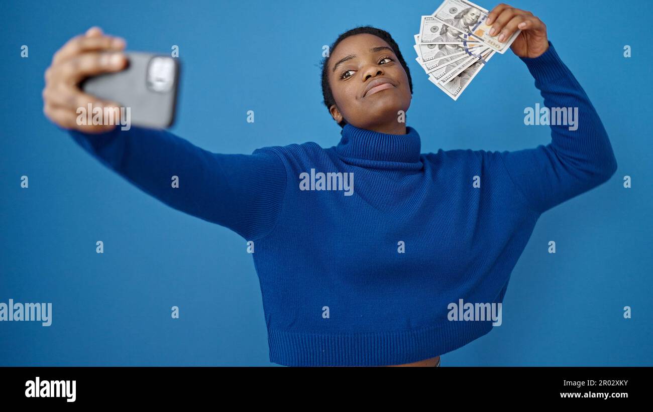 African American Woman Taking Selfie Holding Dollars Over Isolated Blue