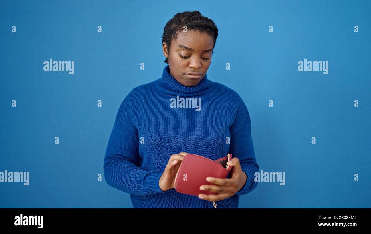 African american woman looking empty wallet over isolated blue ...