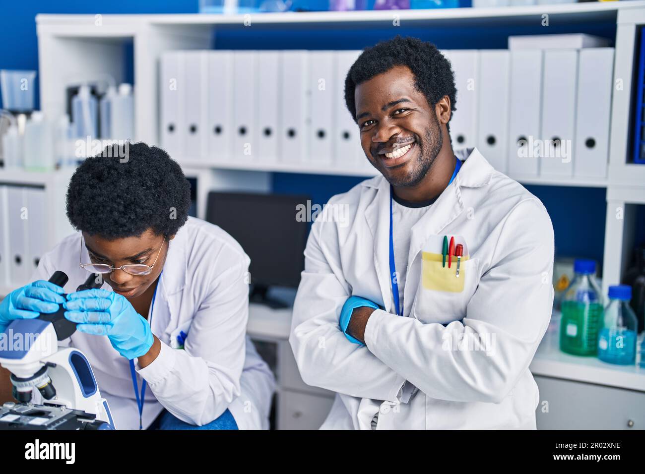 African american man and woman scientists using microscope at ...