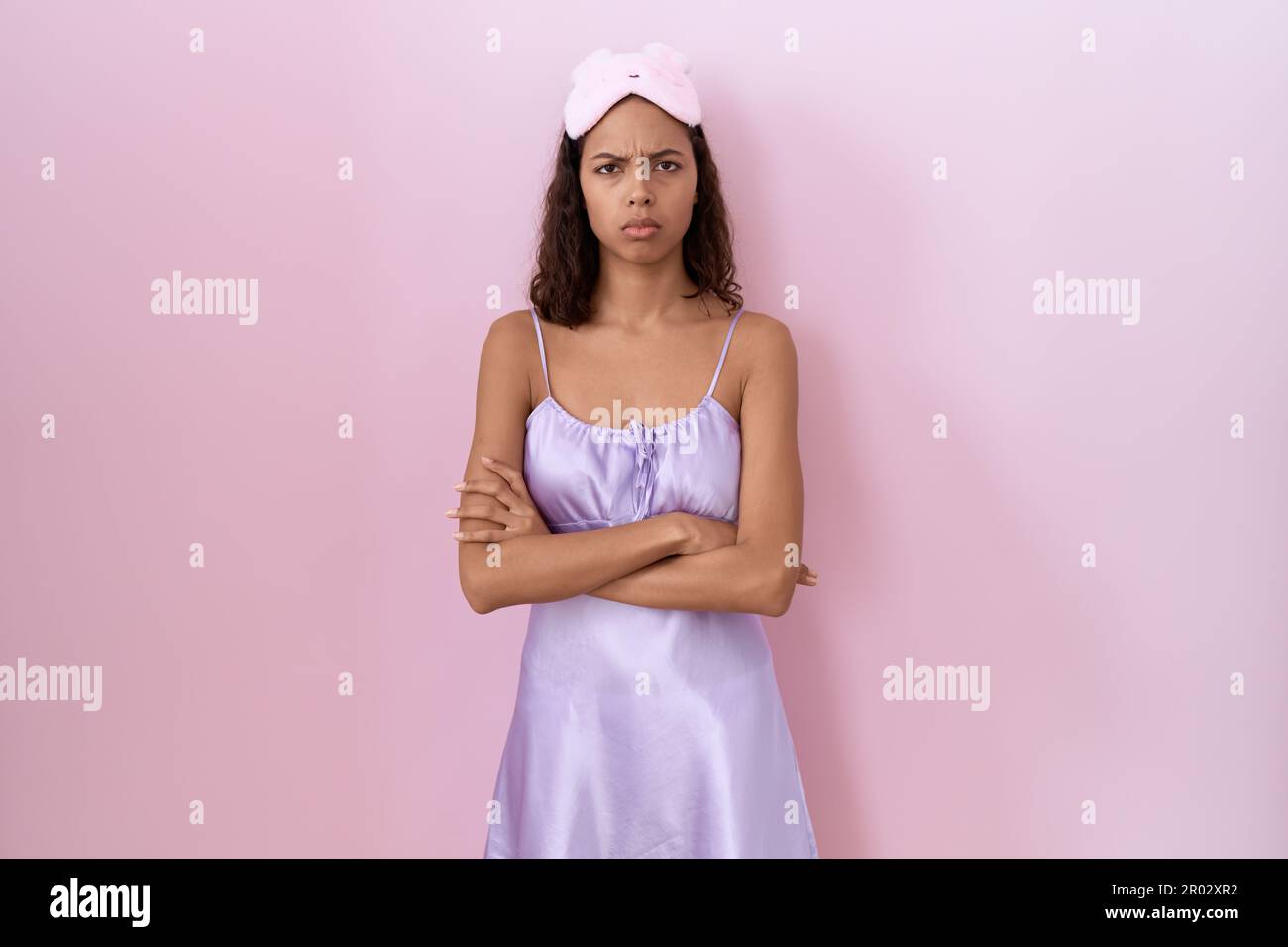 Young hispanic woman wearing sleep mask and nightgown skeptic and ...
