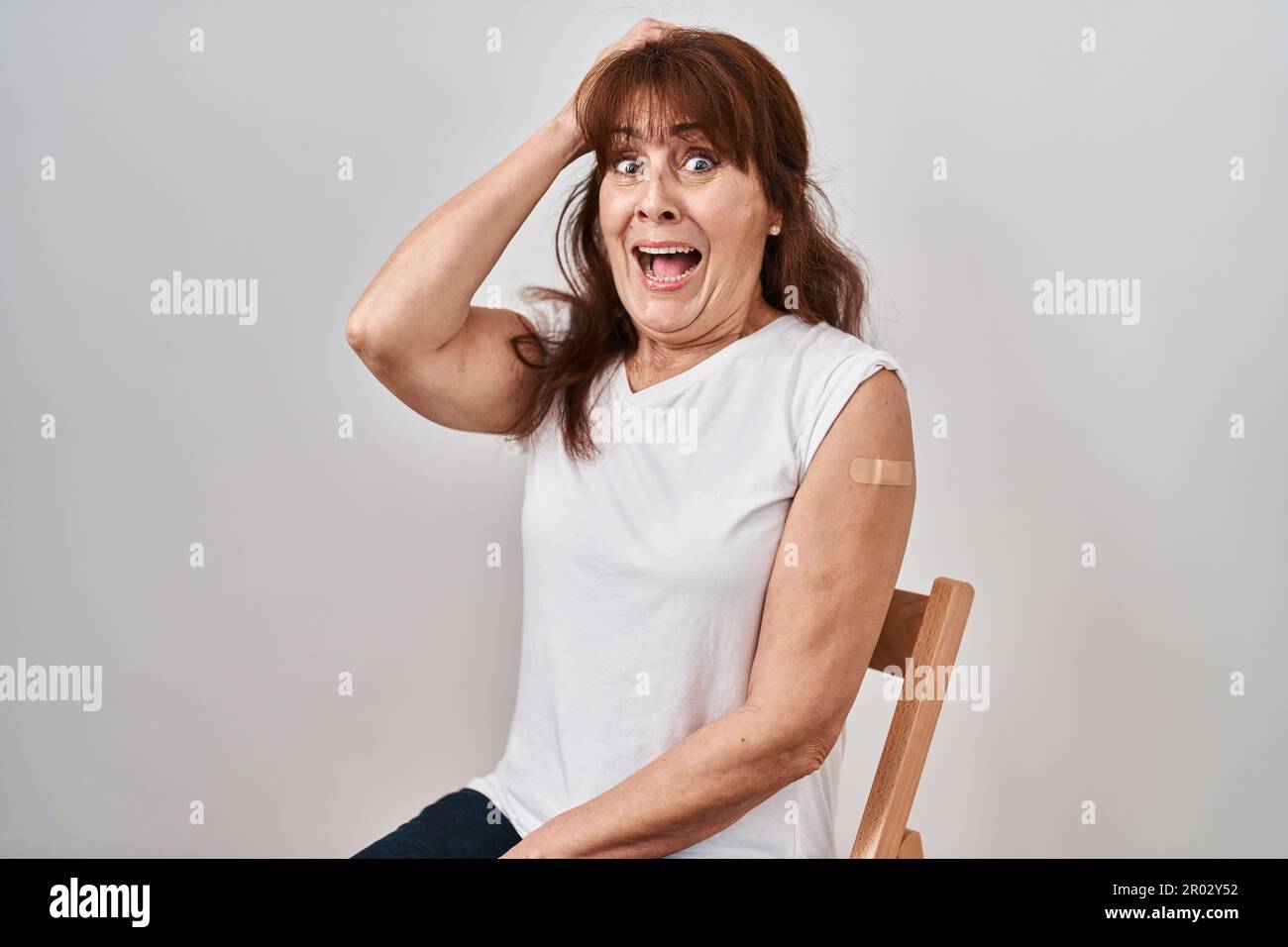 Middle age hispanic woman getting vaccine showing arm with band aid ...