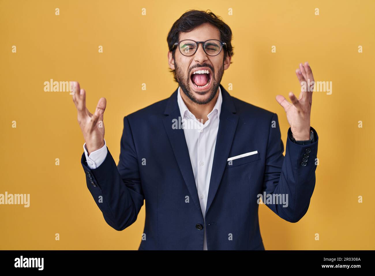 Handsome latin man standing over yellow background celebrating mad and ...
