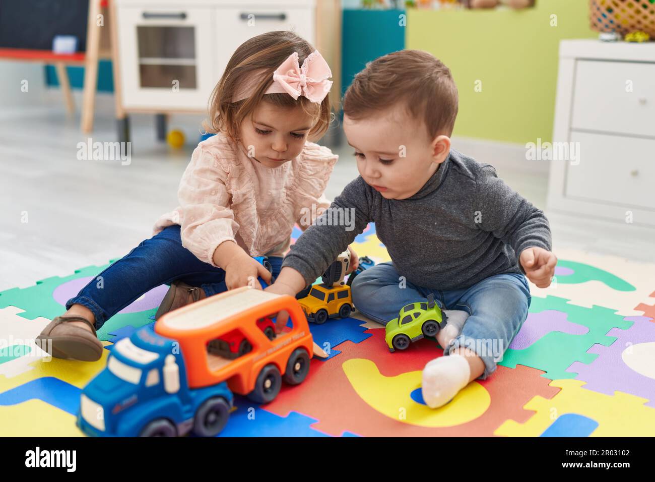 Adorable boy and girl playing with cars toy sitting on floor at ...