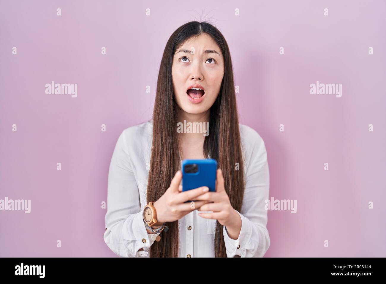 Chinese young woman using smartphone typing message angry and mad ...
