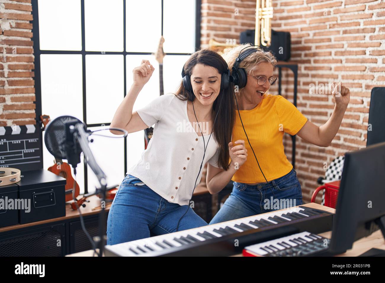 Two women musicians listening to music dancing at music studio Stock ...