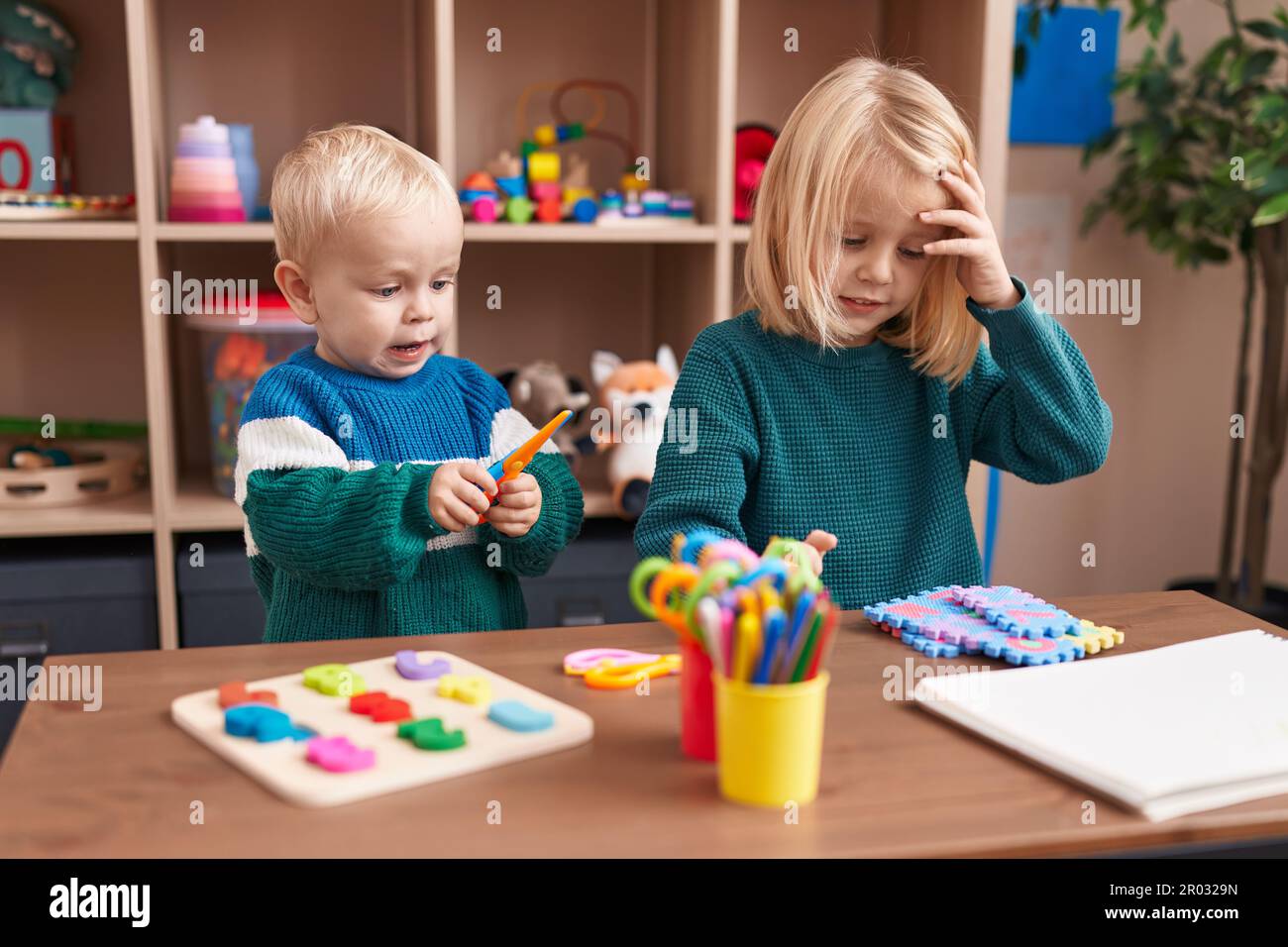 Adorable boy and girl playing with maths puzzle game holding scissors ...