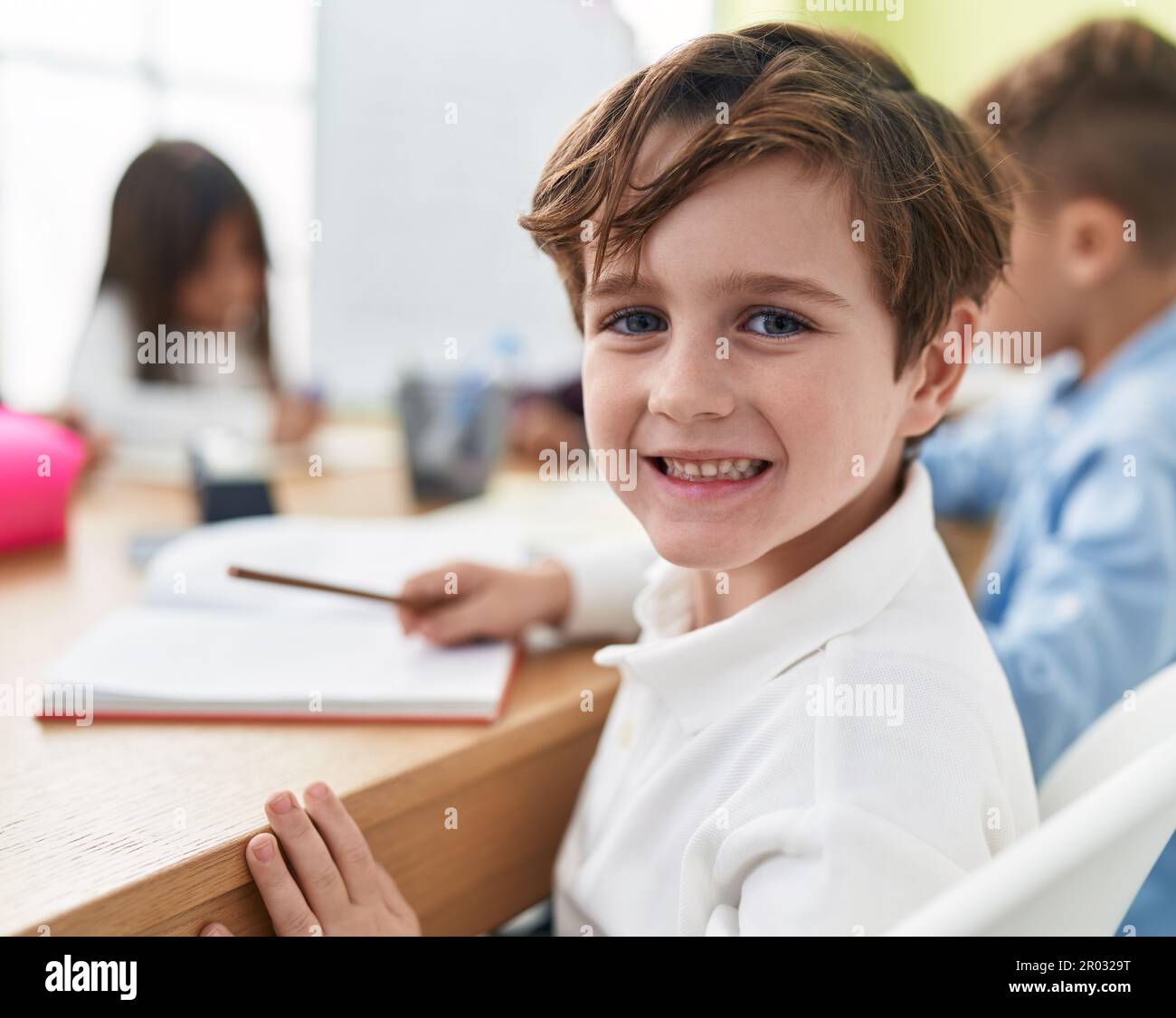 Adorable caucasian boy student writing on notebook studying at ...