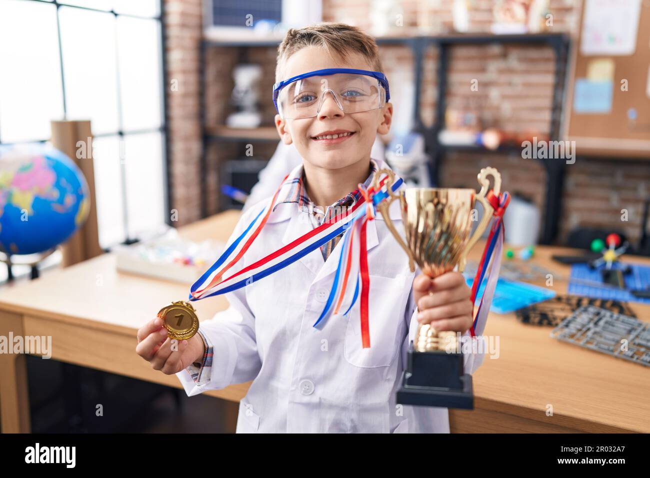 Adorable boys students holding gold medal and cup at laboratory ...