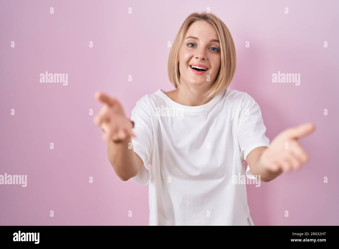 Young caucasian woman standing over pink background smiling cheerful ...