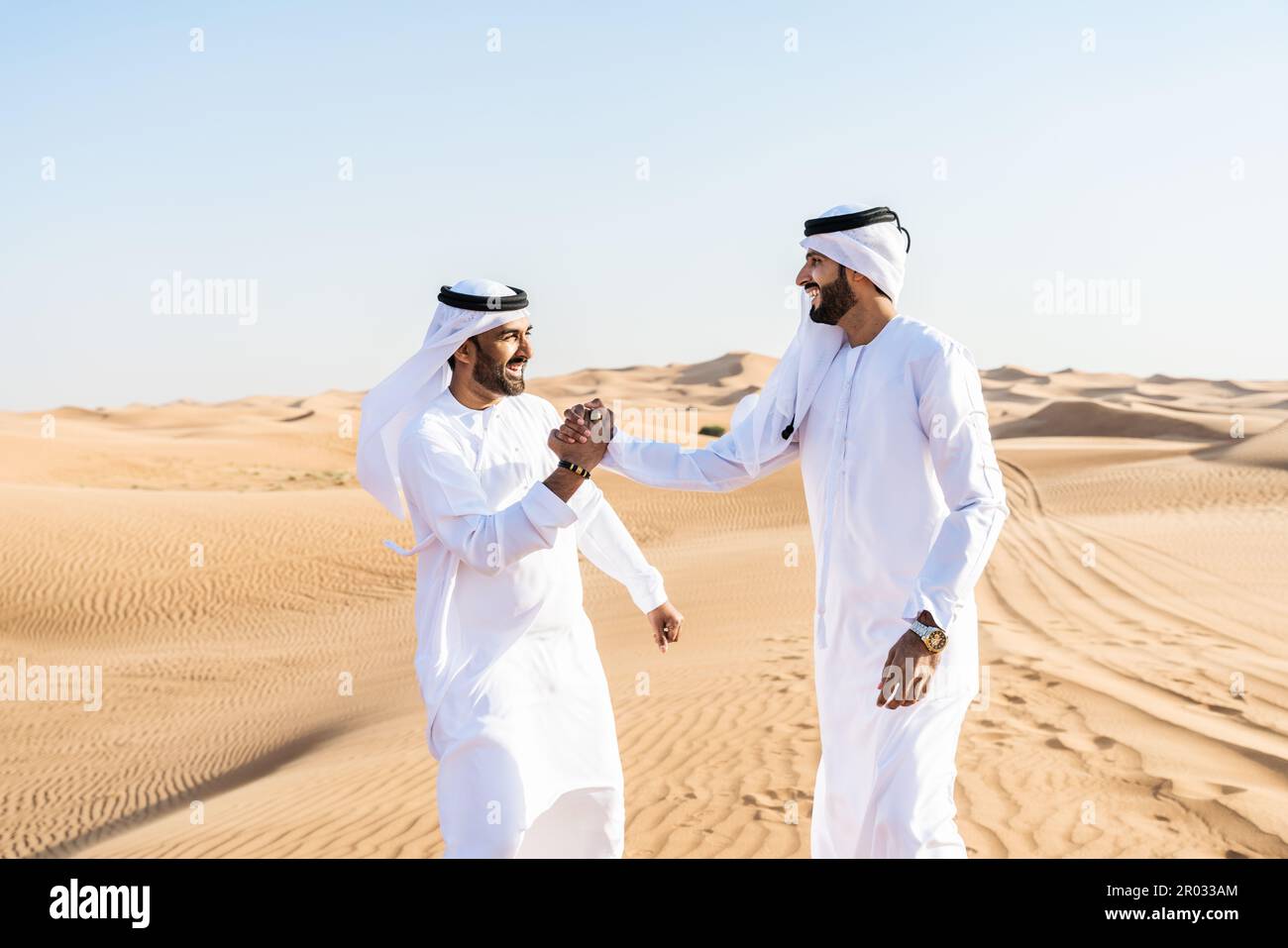 Two middle-eastern men wearing traditional emirati arab kandura bonding ...