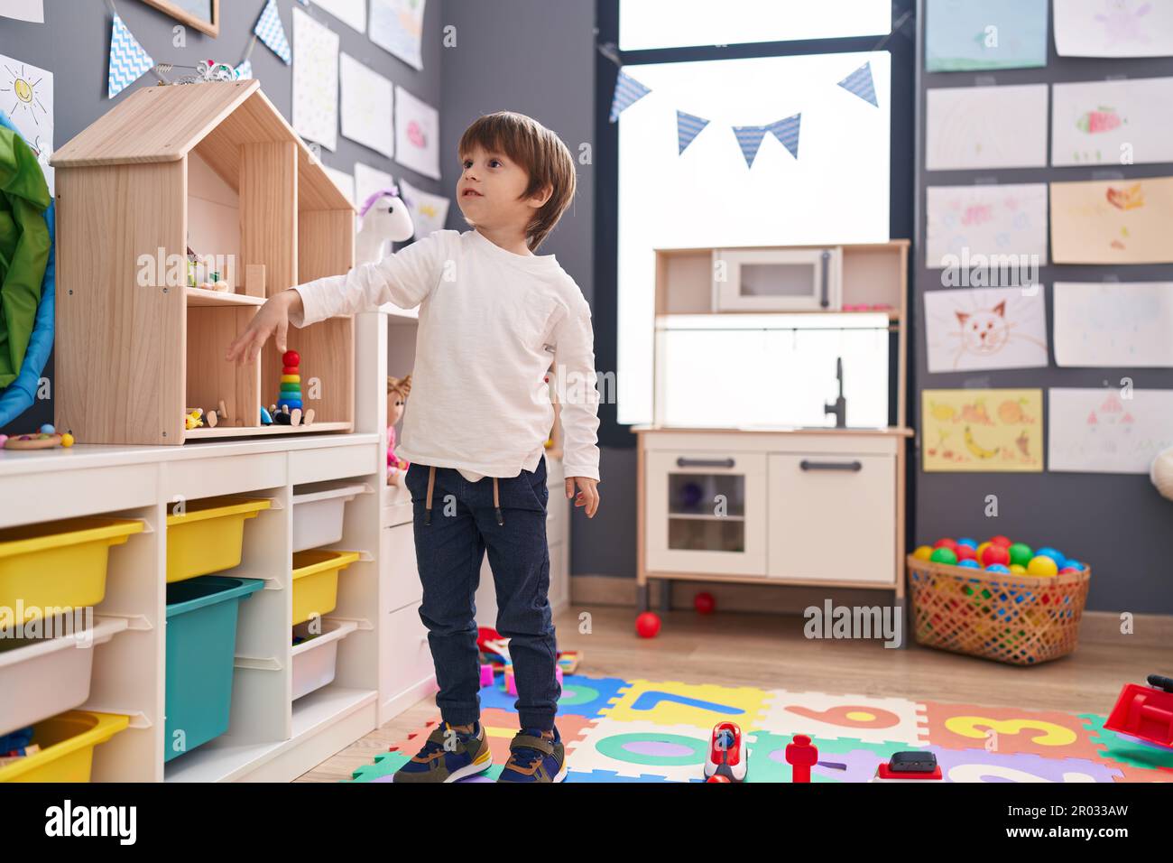 Adorable caucasian boy standing with relaxed expression playing at ...