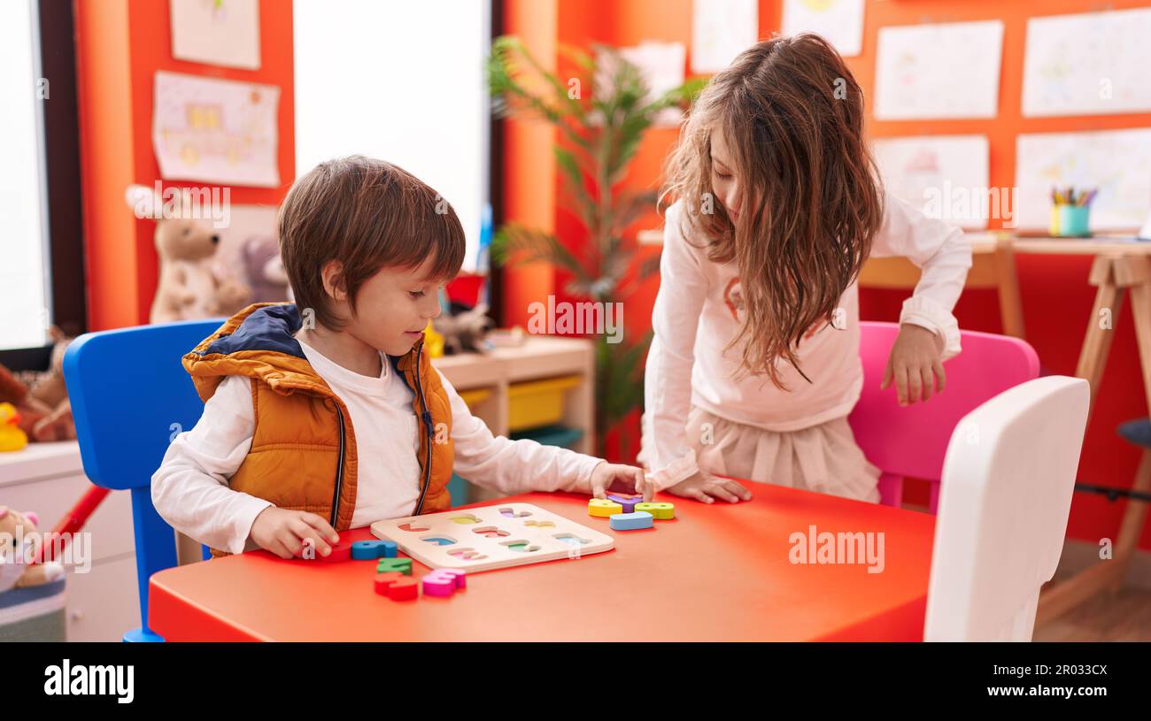 Adorable boy and girl playing with maths puzzle game sitting on table ...