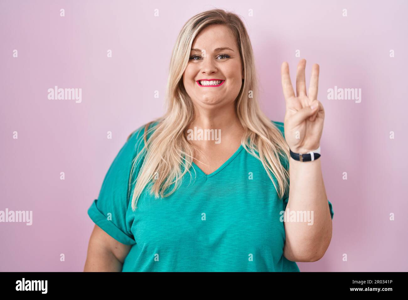 Caucasian plus size woman standing over pink background showing and ...