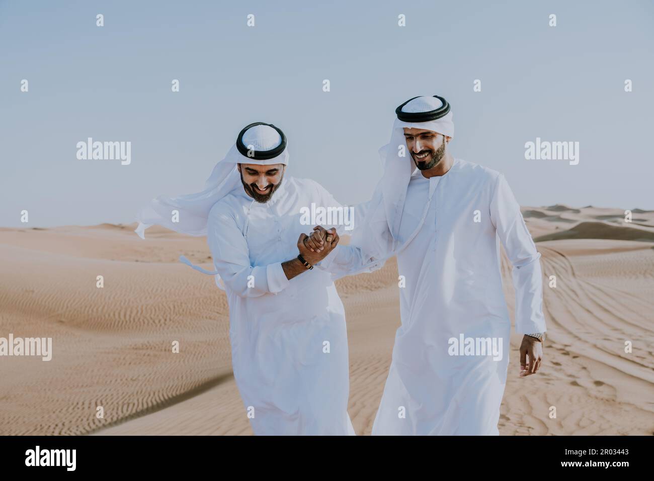 Two middle-eastern men wearing traditional emirati arab kandura bonding ...