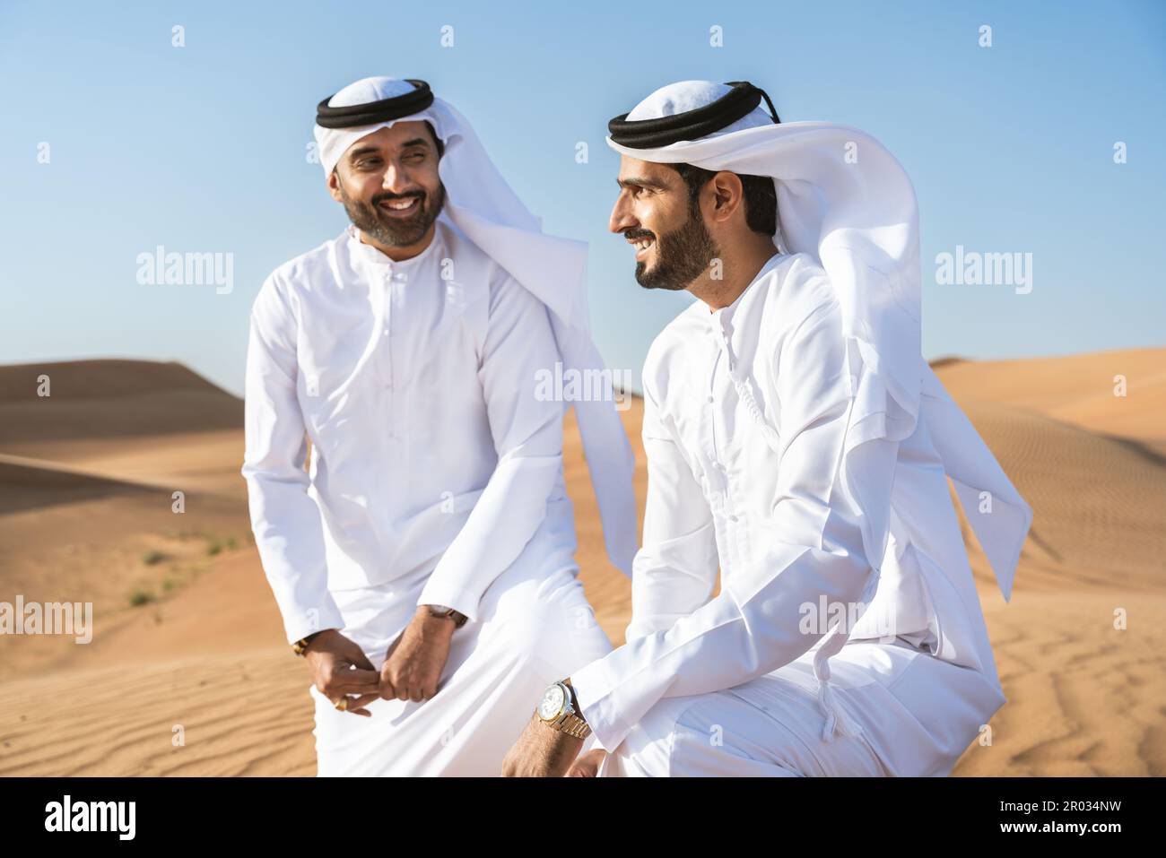 Two middle-eastern men wearing traditional emirati arab kandura bonding ...