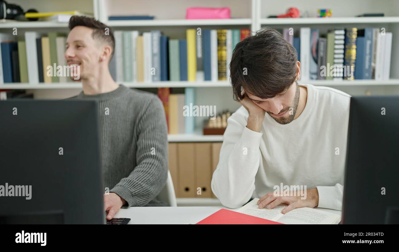 Two men students using computer reading book studying at library university Stock Photo - Alamy