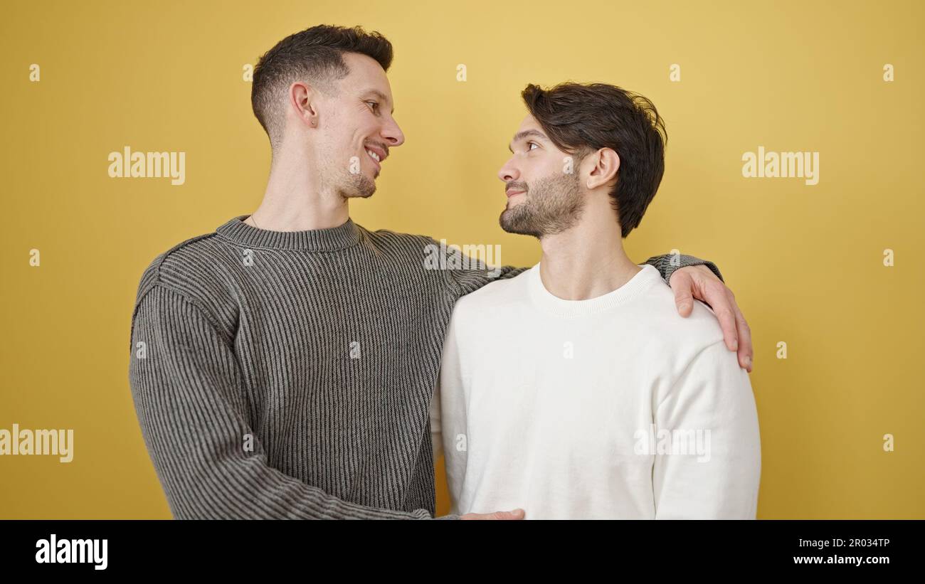 Two men couple hugging each other standing over isolated yellow ...