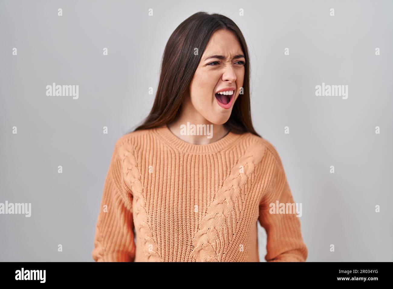 Young brunette woman standing over white background angry and mad ...